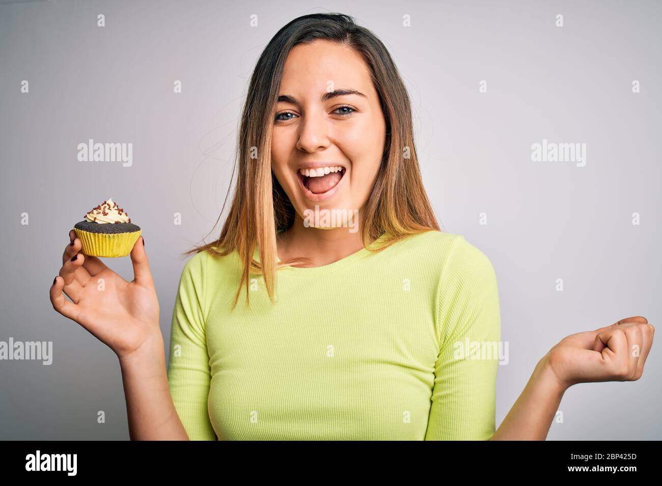 Young beautiful woman with blue eyes eating sweet chocolate cupcake ...