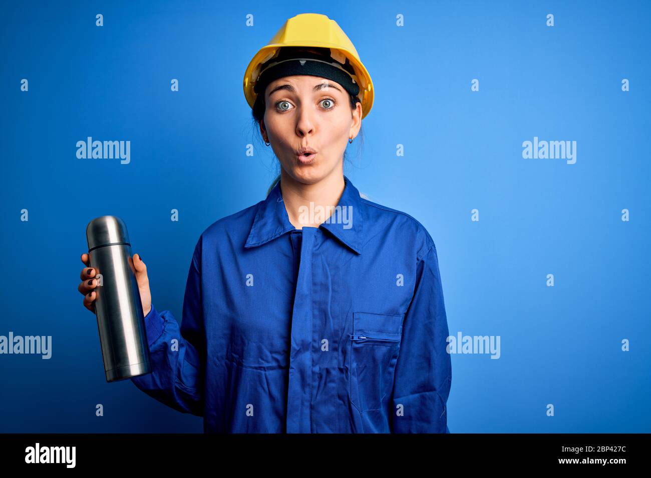 Young beautiful brunette worker woman wearing safety helmet holding ...