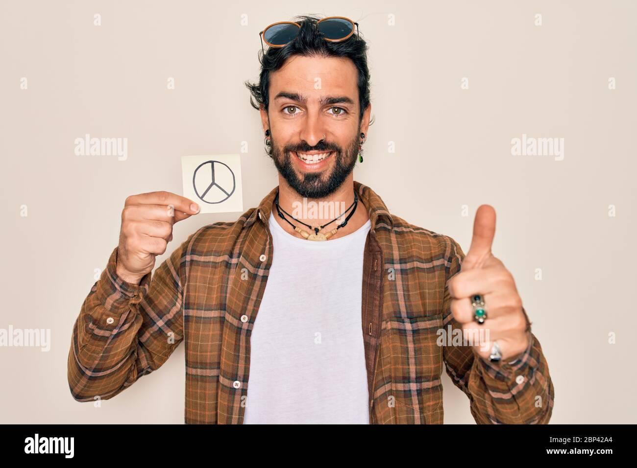 Young handsome hispanic bohemian hipster man with bear holding paper ...