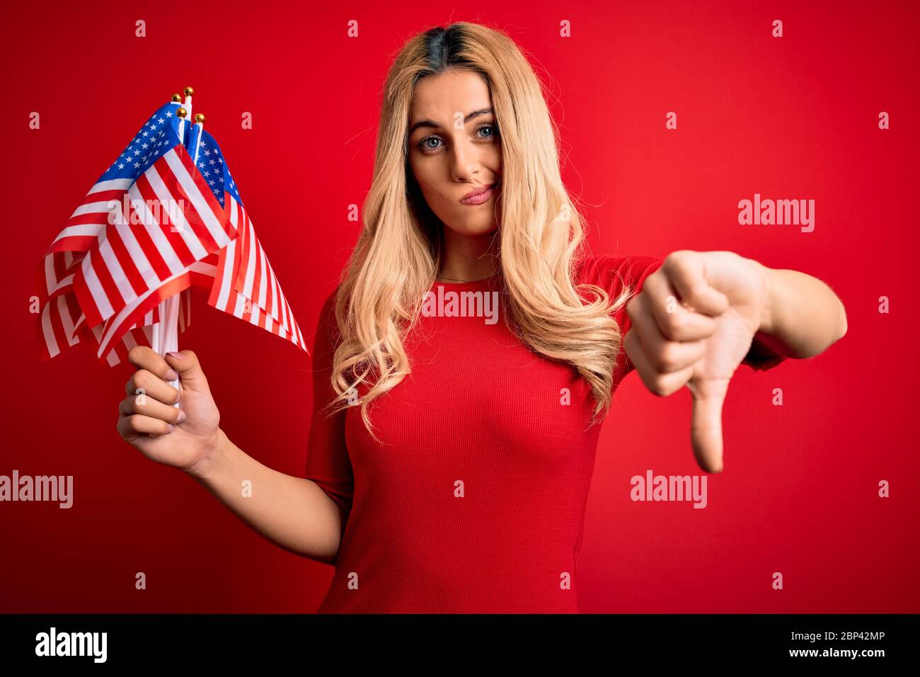 Beautiful blonde patriotic woman holding united states flags ...