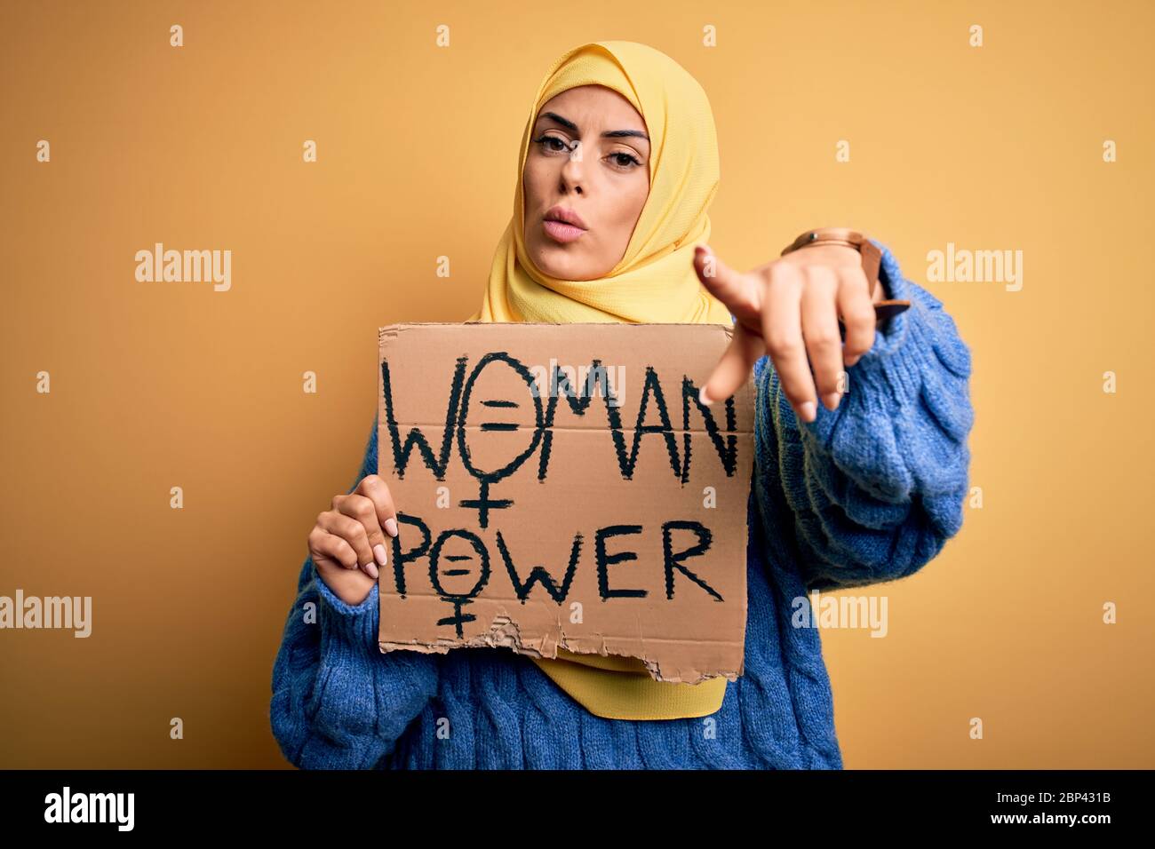 Young beautiful arab woman wearing islamic hijab holding banner with ...
