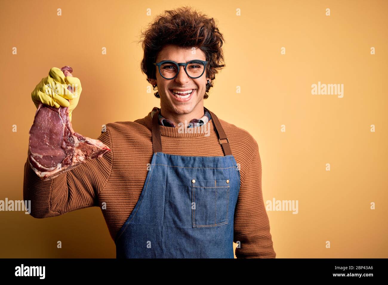 Young handsome butcher man holding meet steak standing over isolated ...