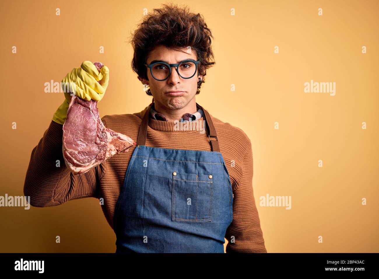 Young handsome butcher man holding meet steak standing over isolated ...
