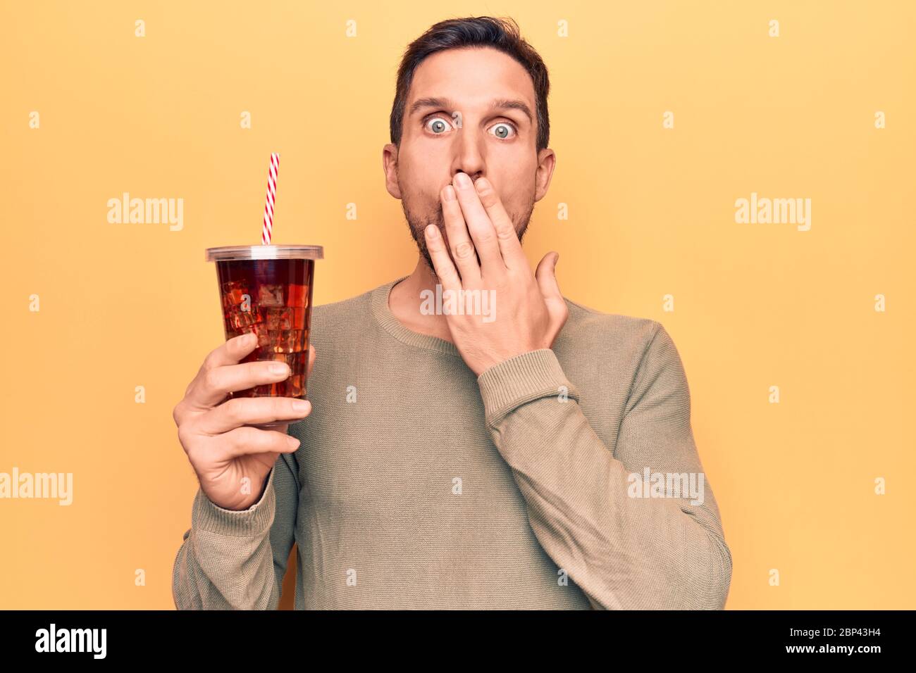 Young handsome man drinking cola refreshment beverage over isolated ...