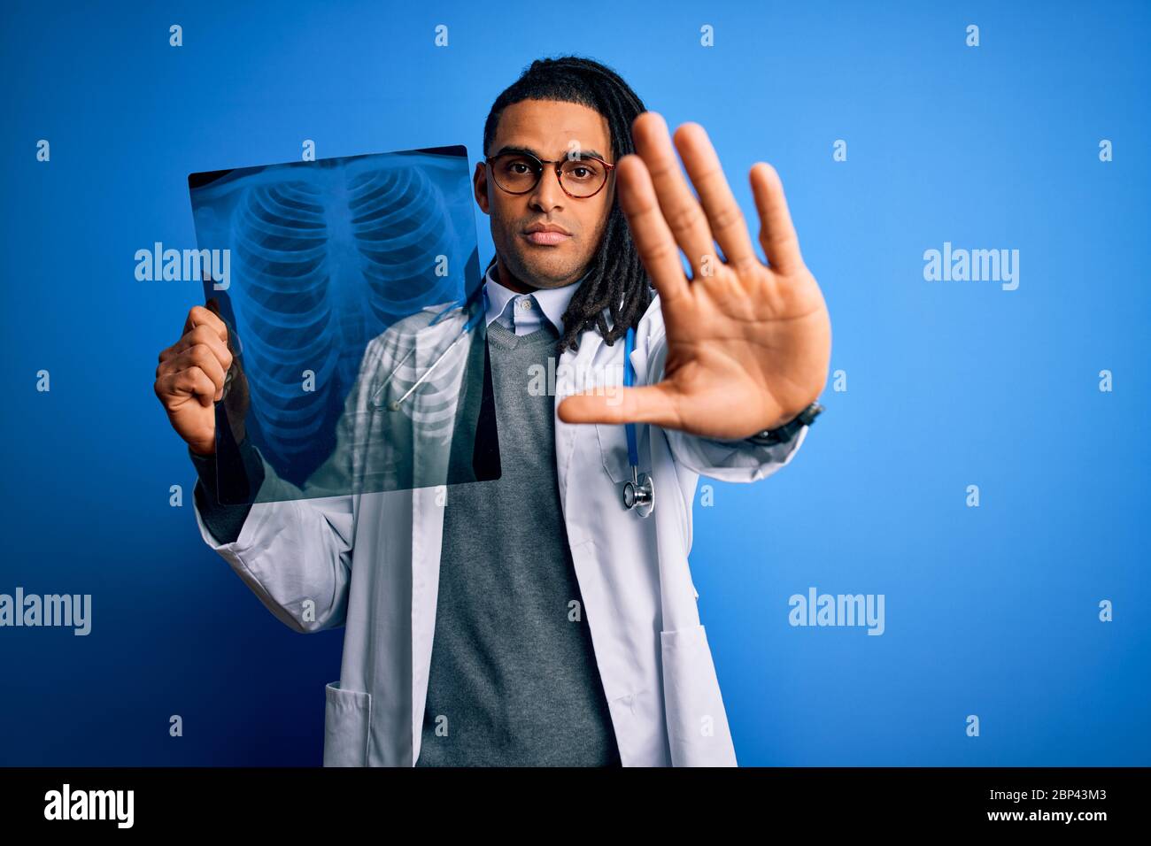 Young african american afro doctor man with dreadlocks holding chest ...