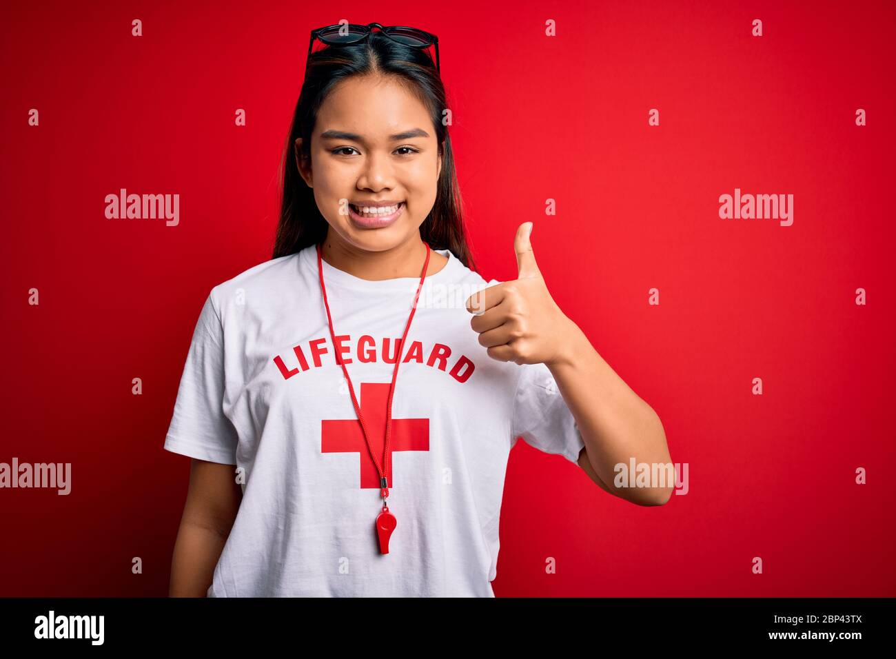 Young asian lifeguard girl wearing t-shirt with red cross using whistle ...