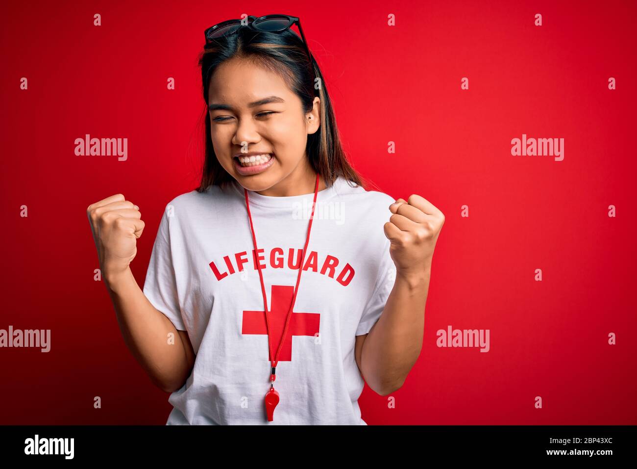 Young asian lifeguard girl wearing t-shirt with red cross using whistle ...