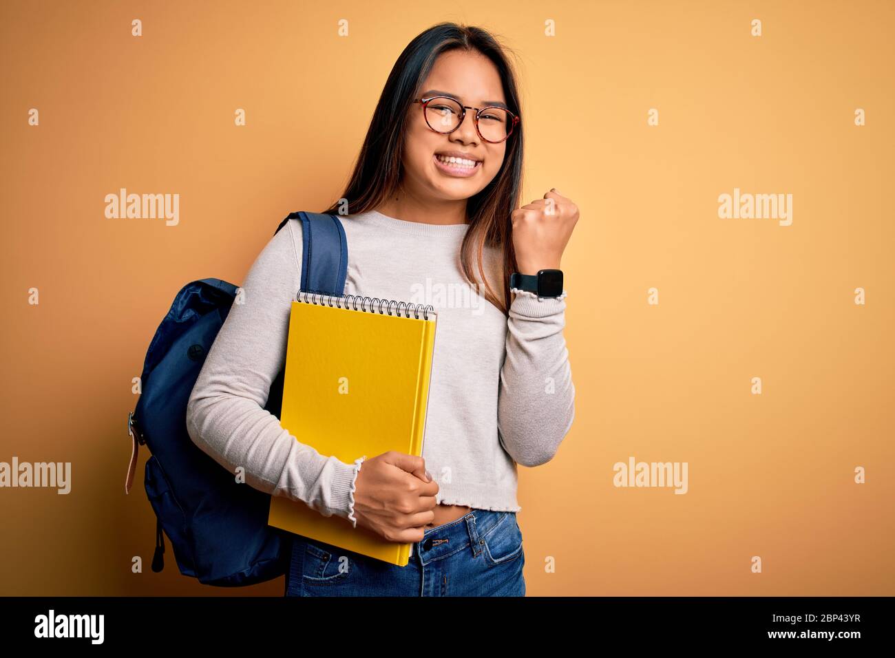 Young smart asian student girl wearing backpack holding notebook over ...