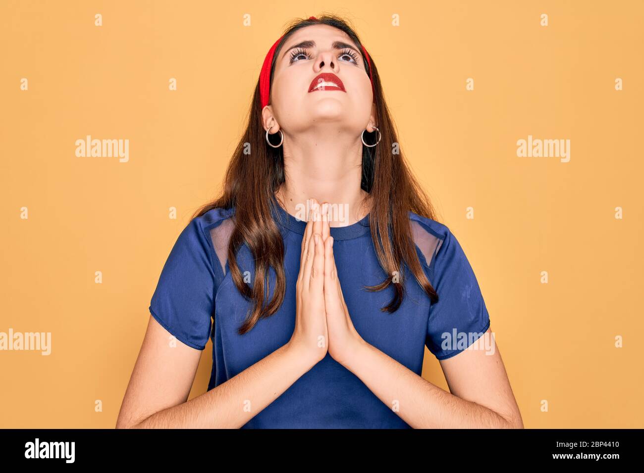 Young beautiful brunette woman wearing red lips over yellow background ...