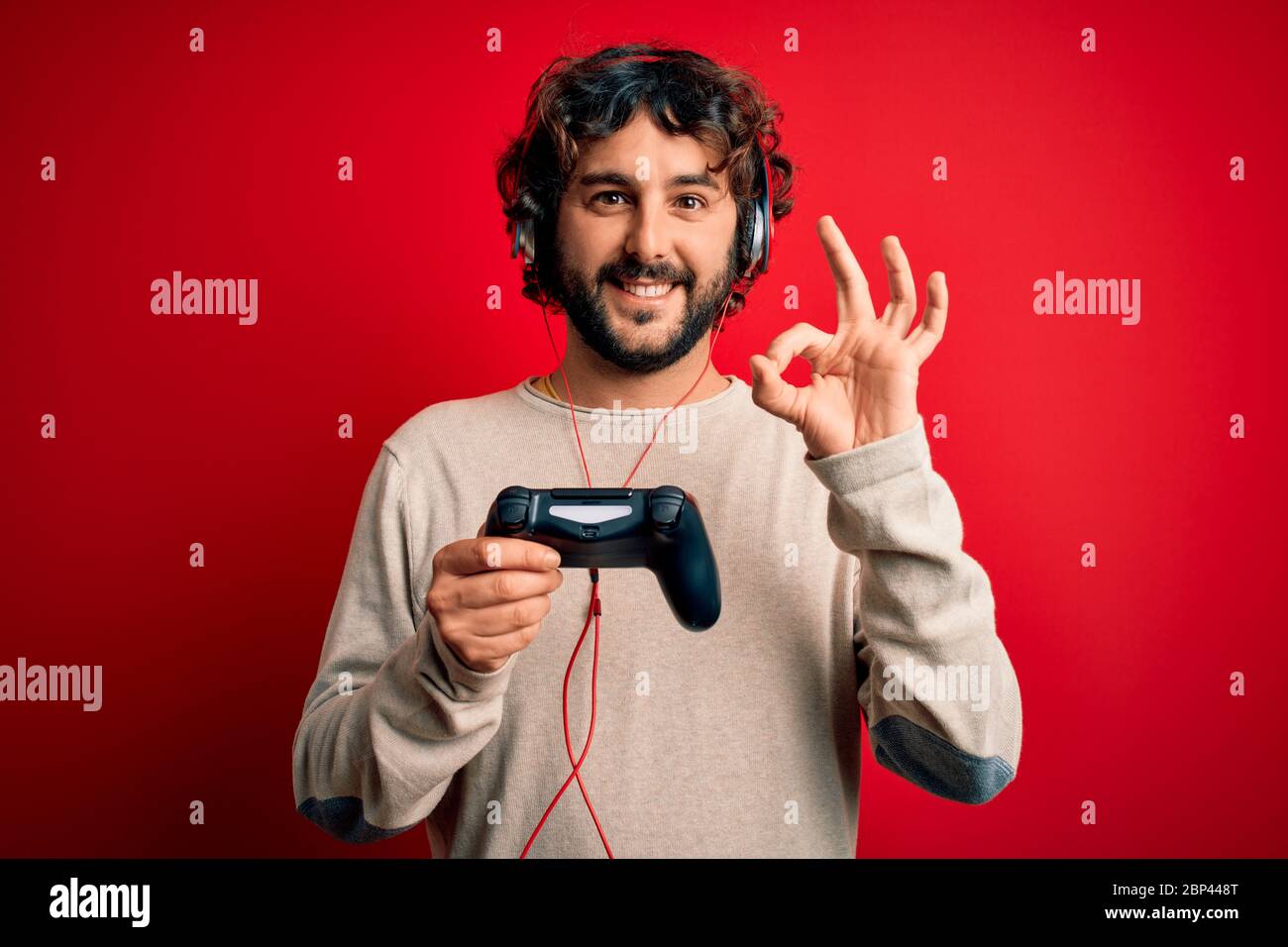 Young gamer man with curly hair and beard playing video game using ...