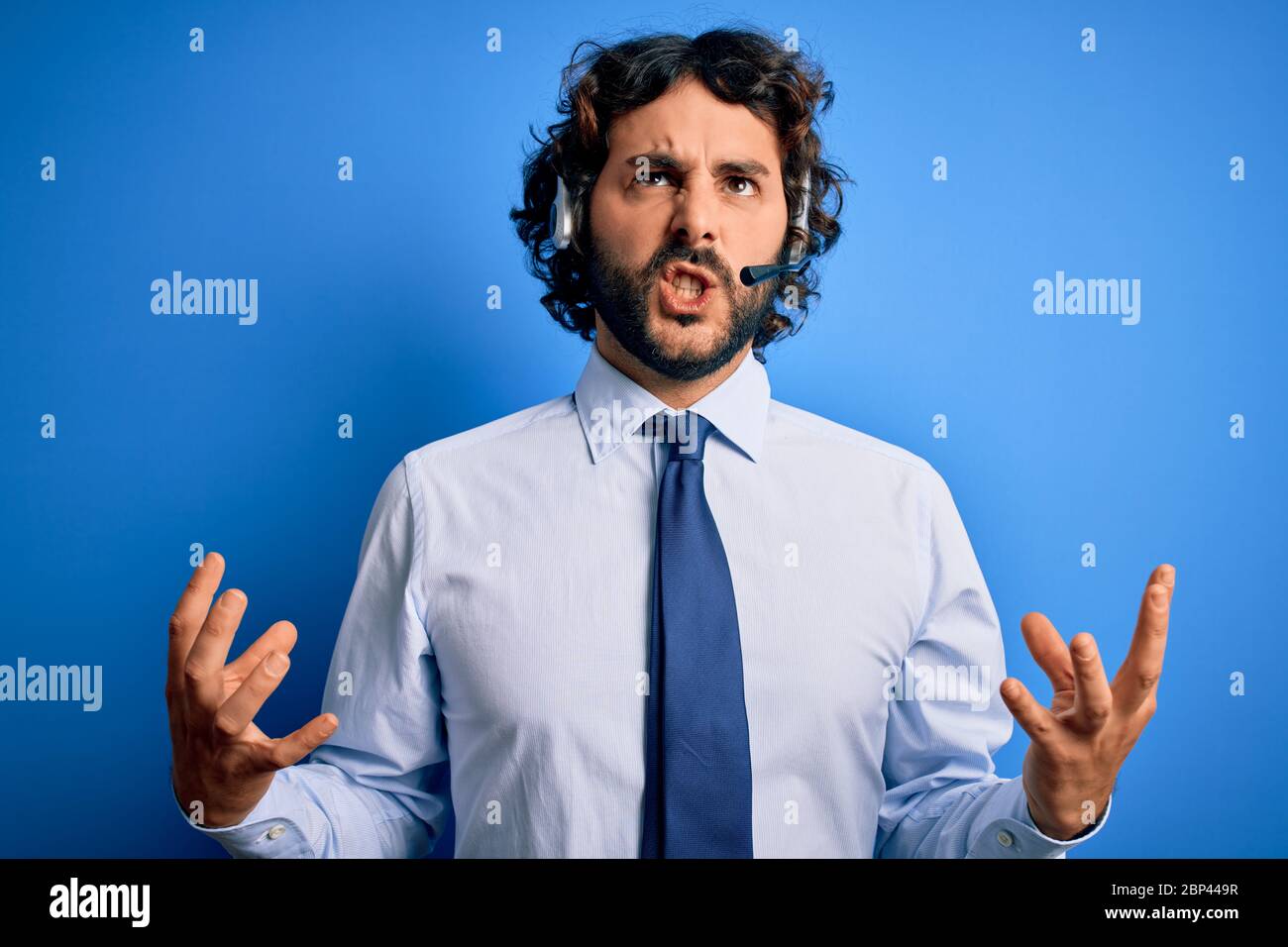 Young handsome call center agent man with beard working using headset ...