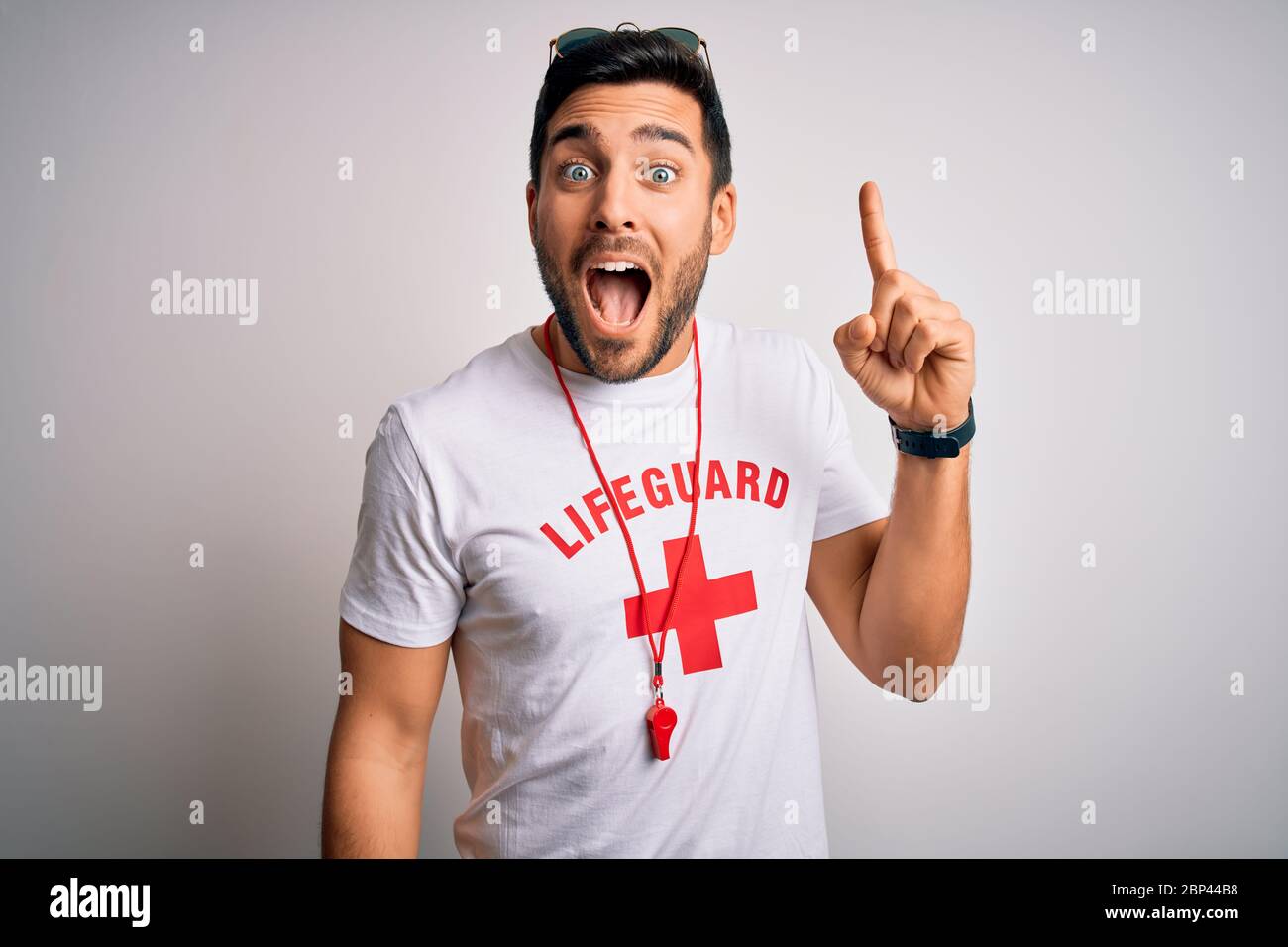 Young handsome lifeguard man with beard wearing t-shirt with red cross ...