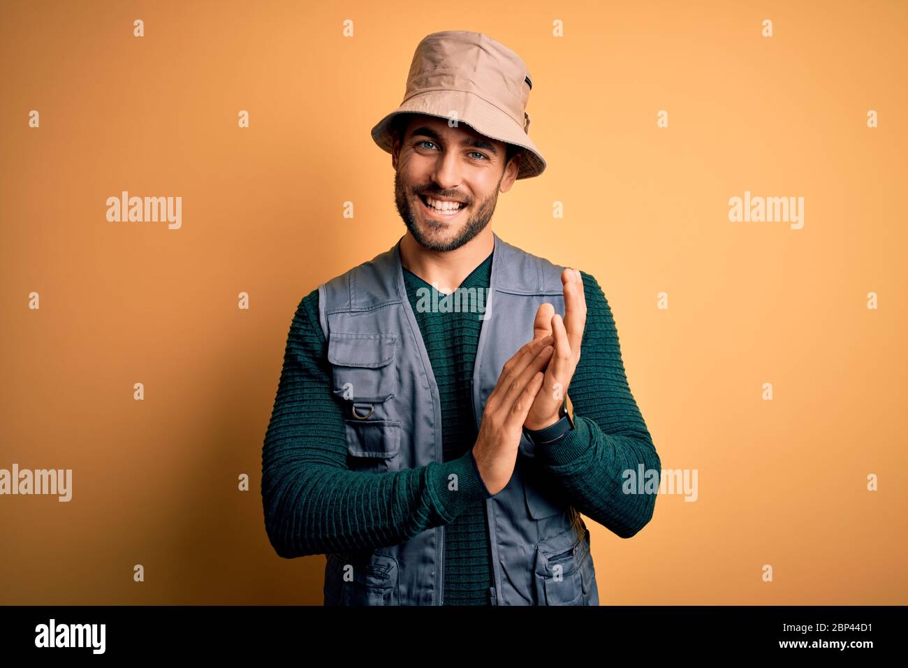 Handsome tourist man with beard on vacation wearing explorer hat over ...