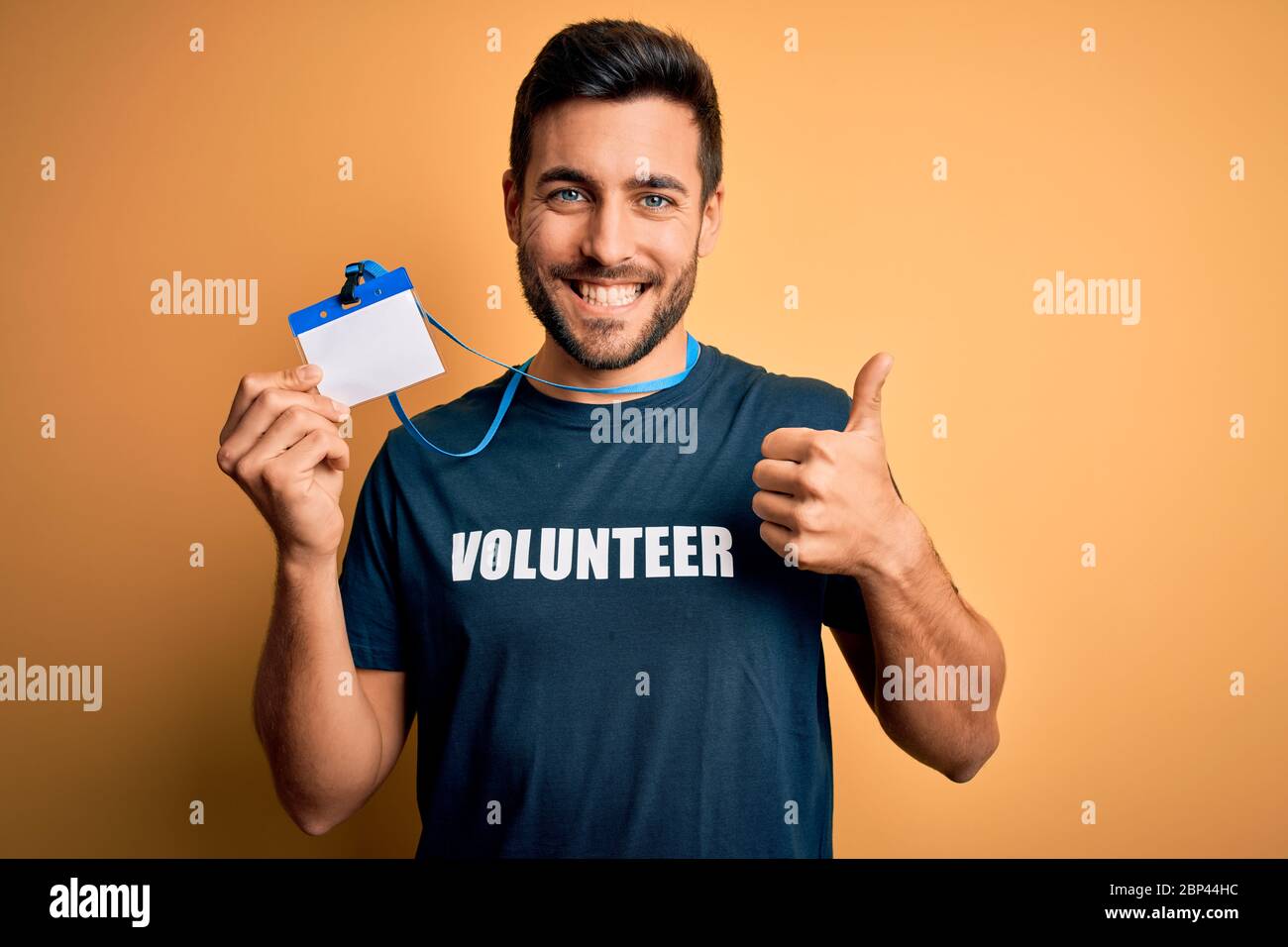 Handsome volunteer man with beard holding id card identification over ...