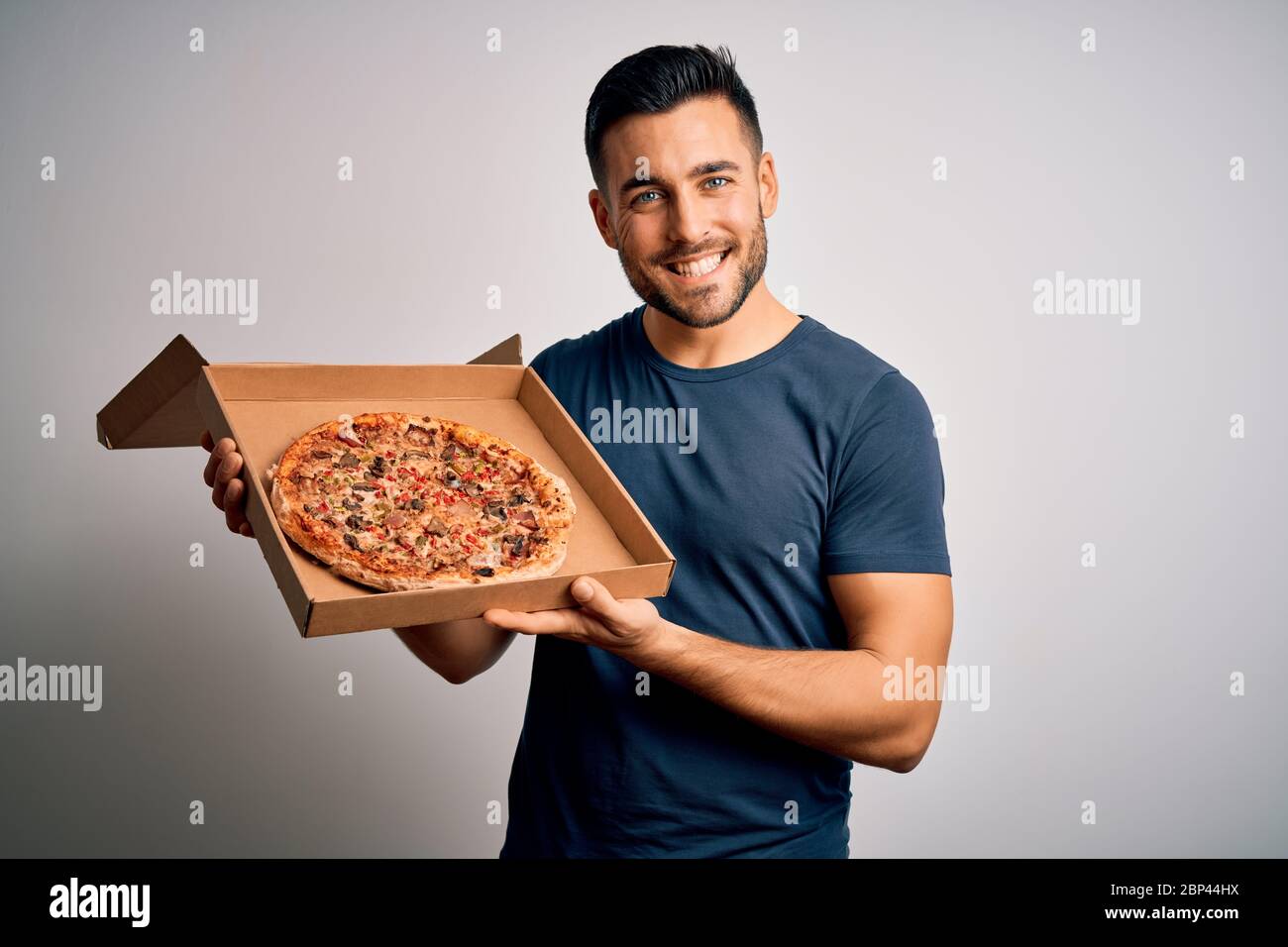 Young handsome man holding delivery box with delicious Italian pizza ...