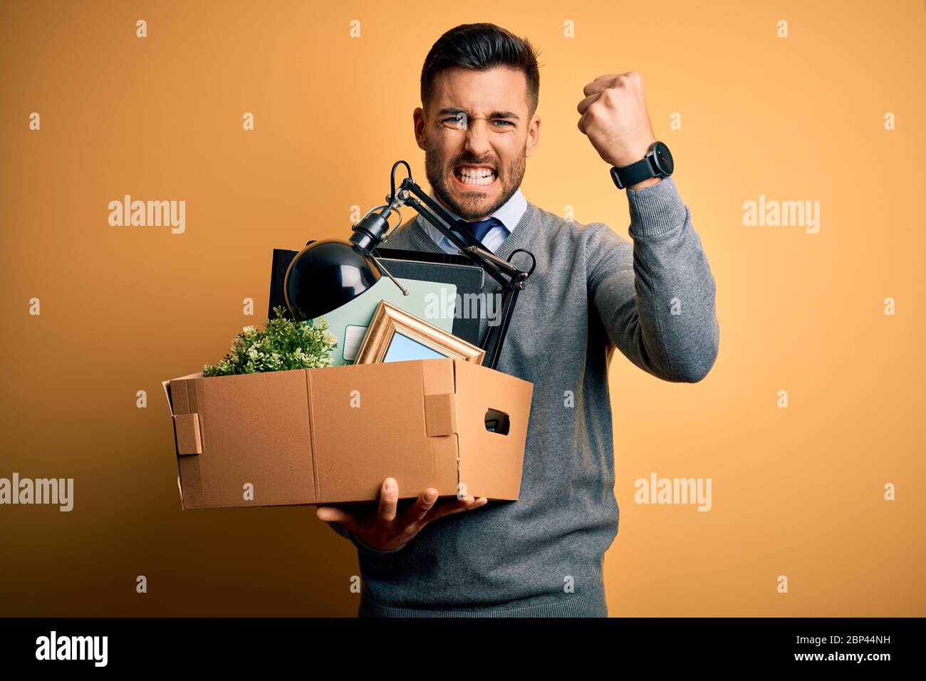 Young business man holding office box being fired from job over yellow ...