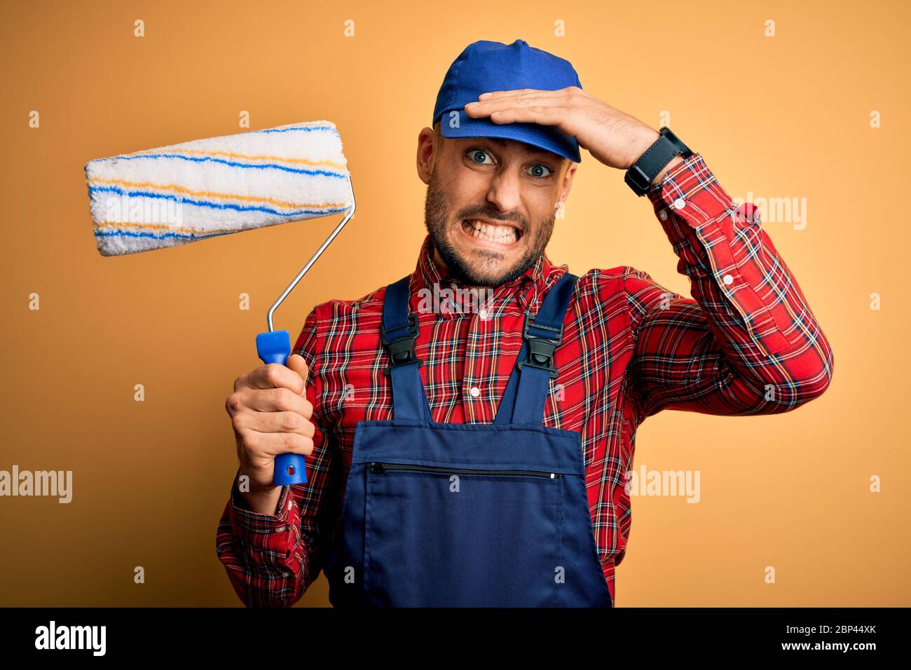 Young handsome painter man painting wall using roller over isolated ...