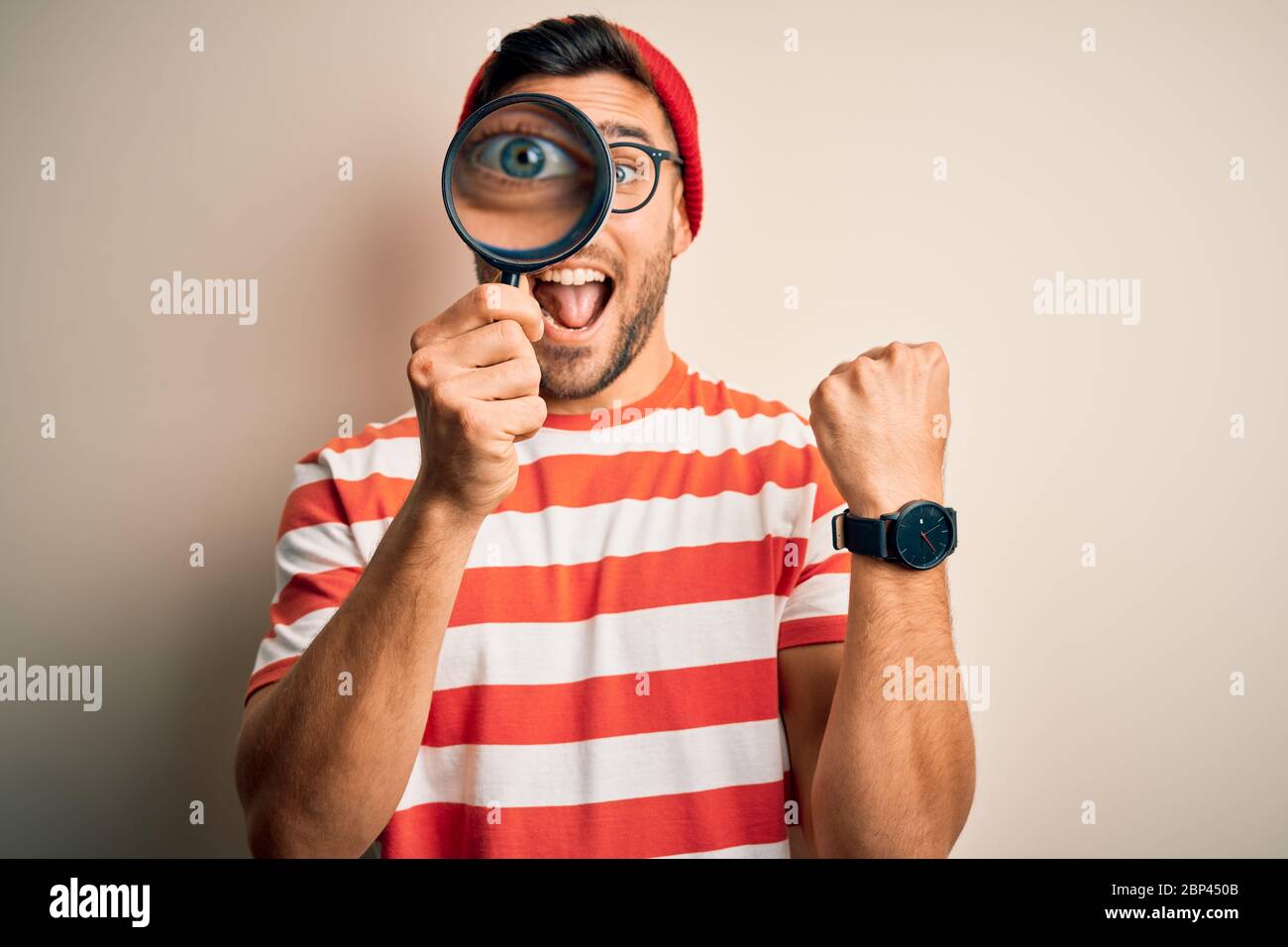 Young detective man looking through magnifying glass over isolated ...