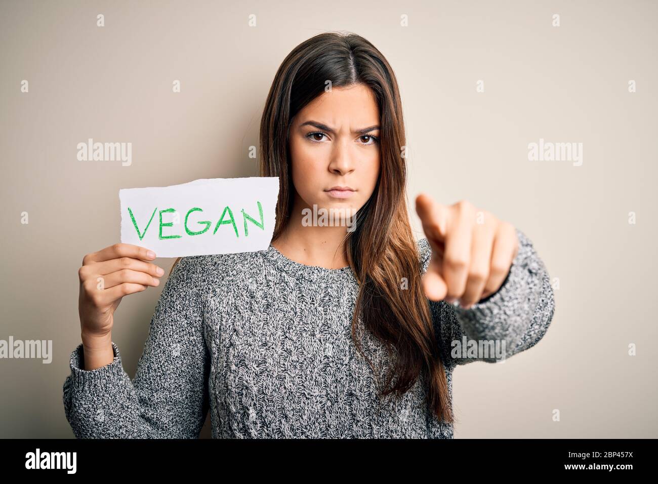 Young beautiful girl holding paper with vegan message over isolated ...