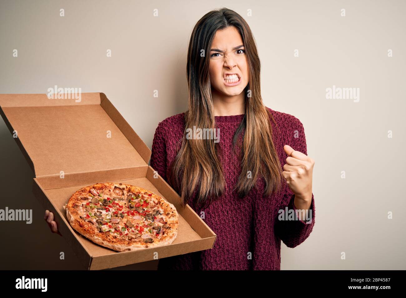 Young beautiful girl holding delivery box with Italian pizza standing ...