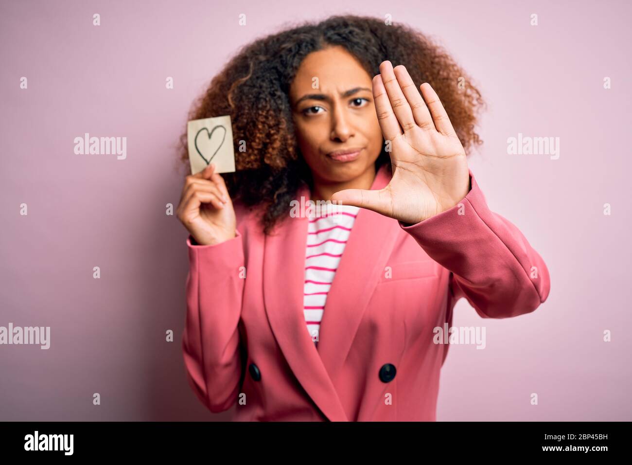Young african american woman with afro hair holding paper with heart ...