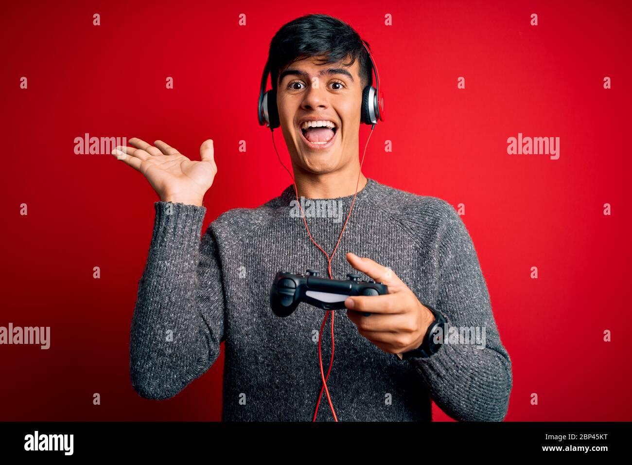 Young handsome gamer man playing video game using joystick and ...