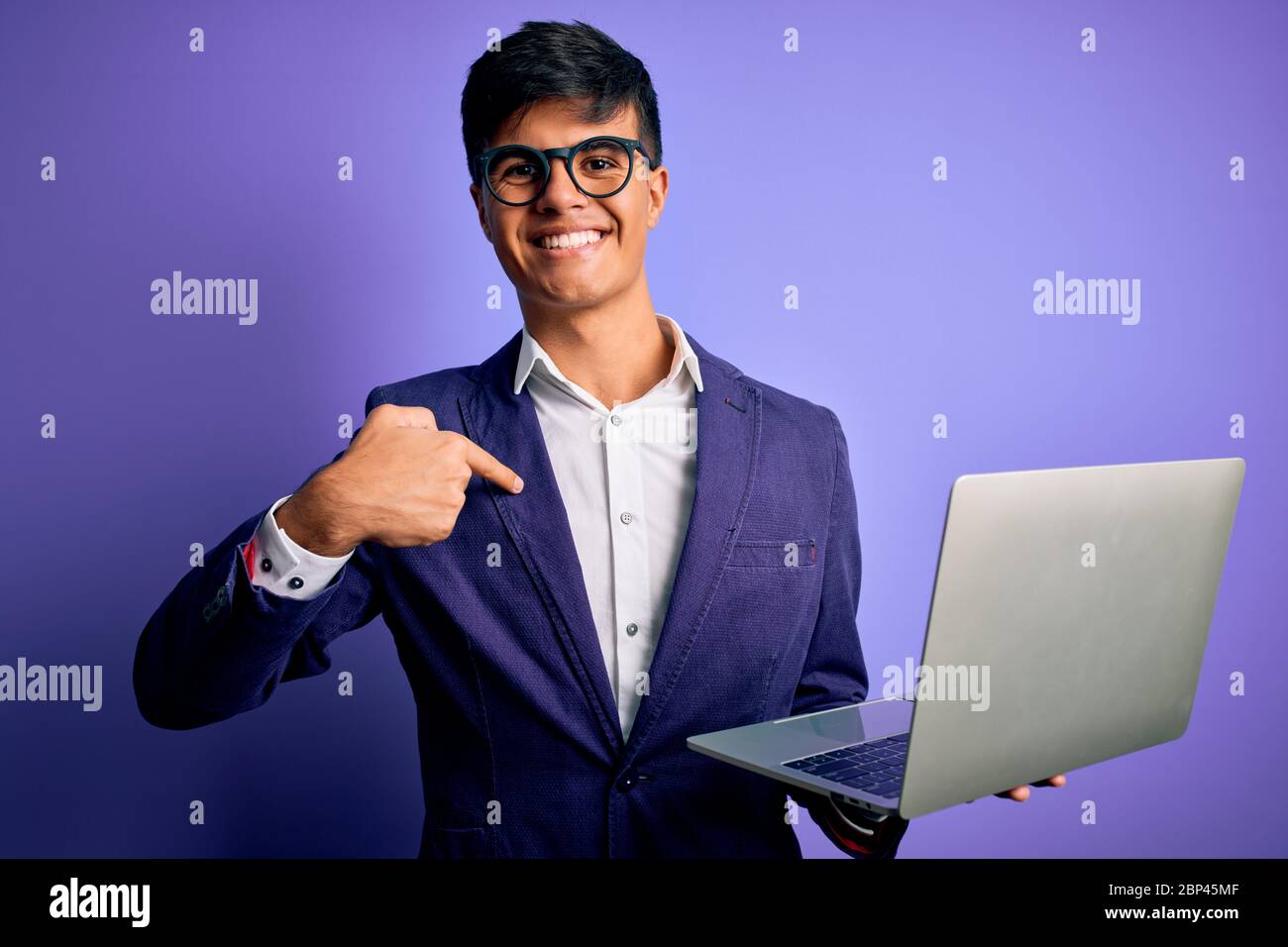 Young handsome business man wearing glasses working using laptop over ...