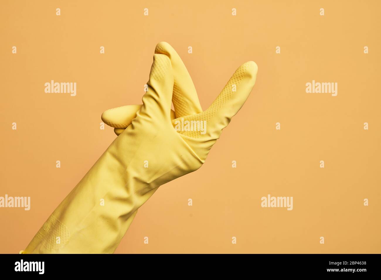 Hand of caucasian young man with cleaning glove over isolated yellow ...