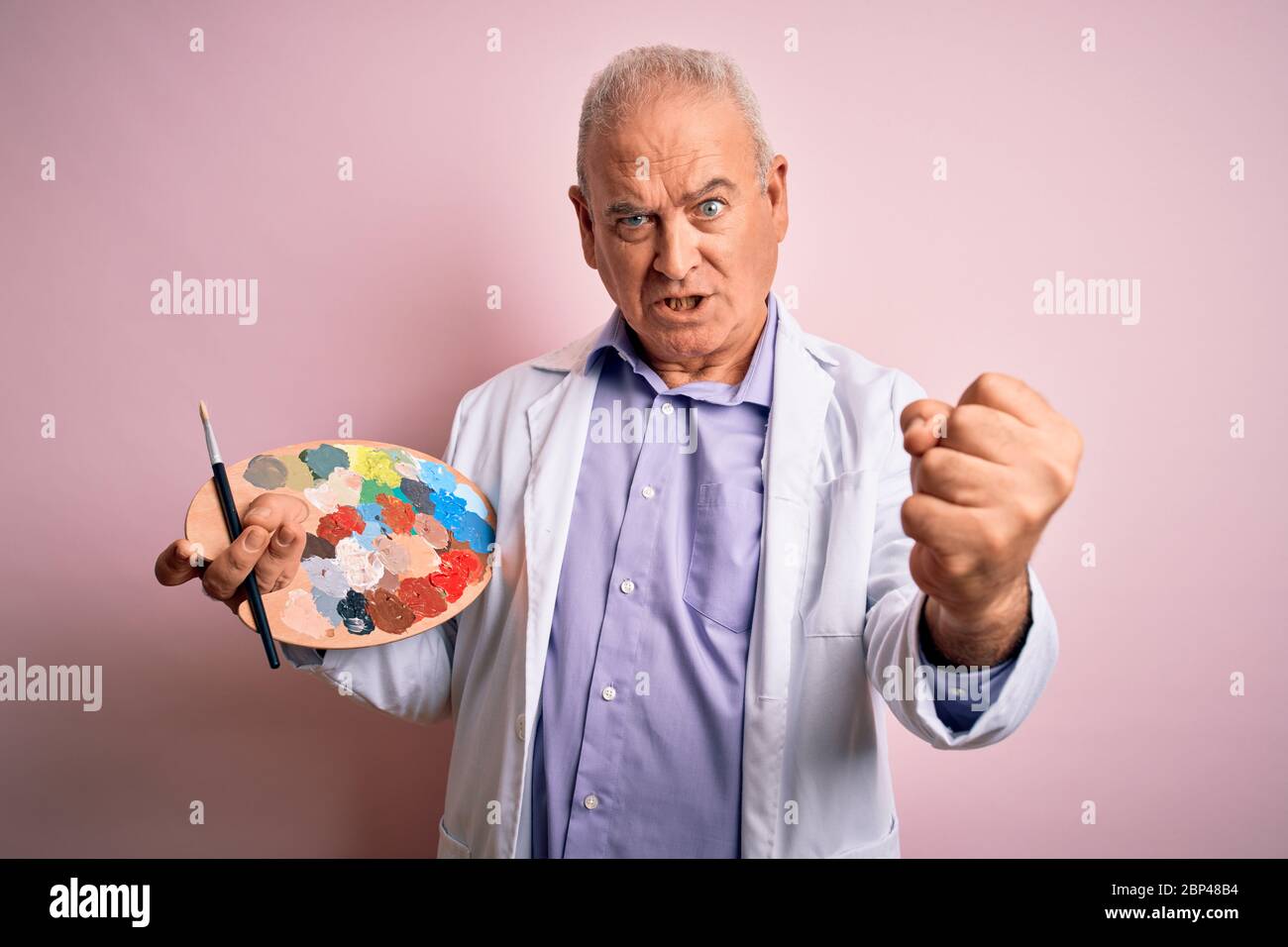 Middle age artist man painting using paintbrush and palette with colors ...