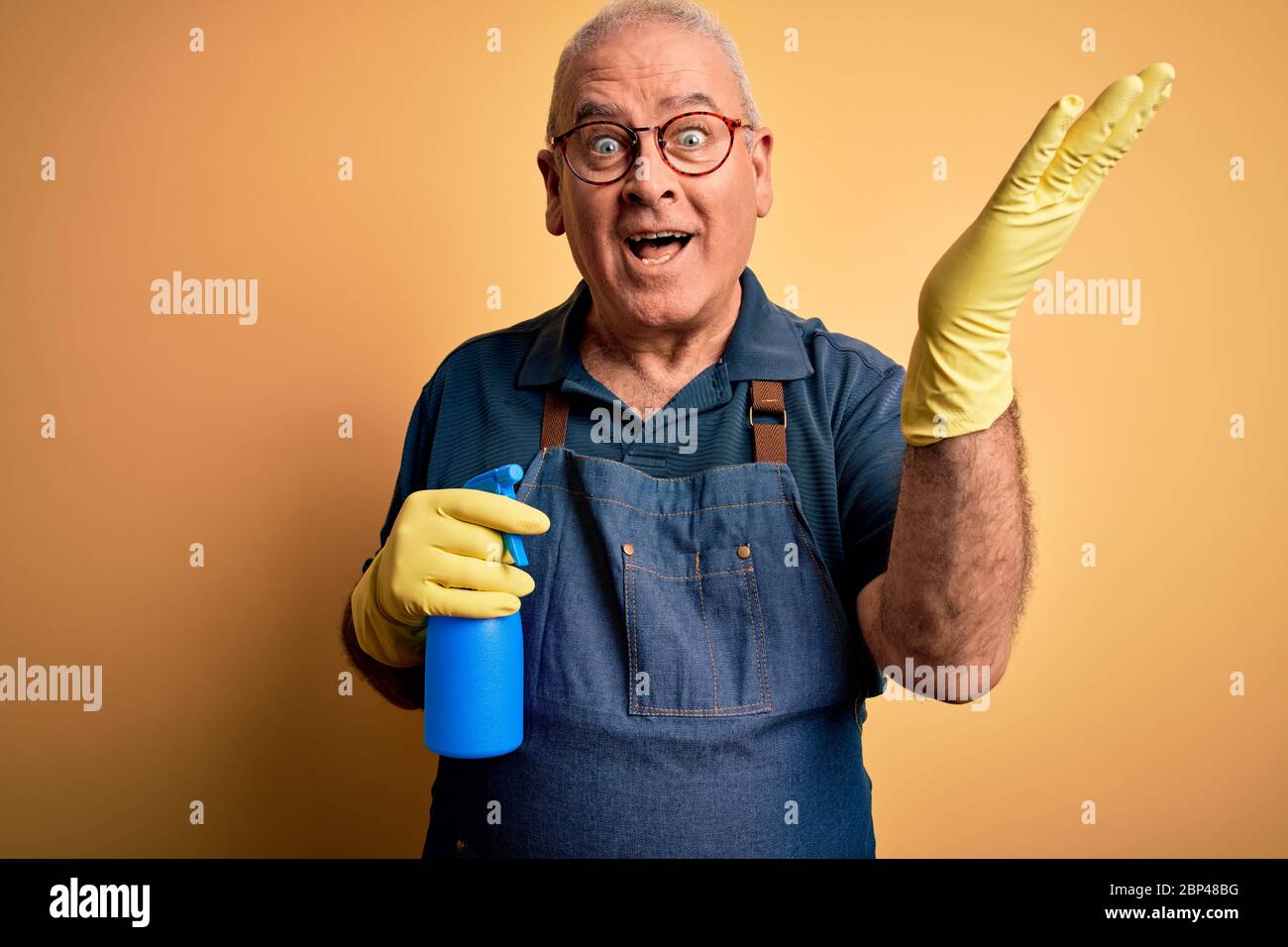 Middle age hoary cleaner man cleaning wearing apron and gloves using ...