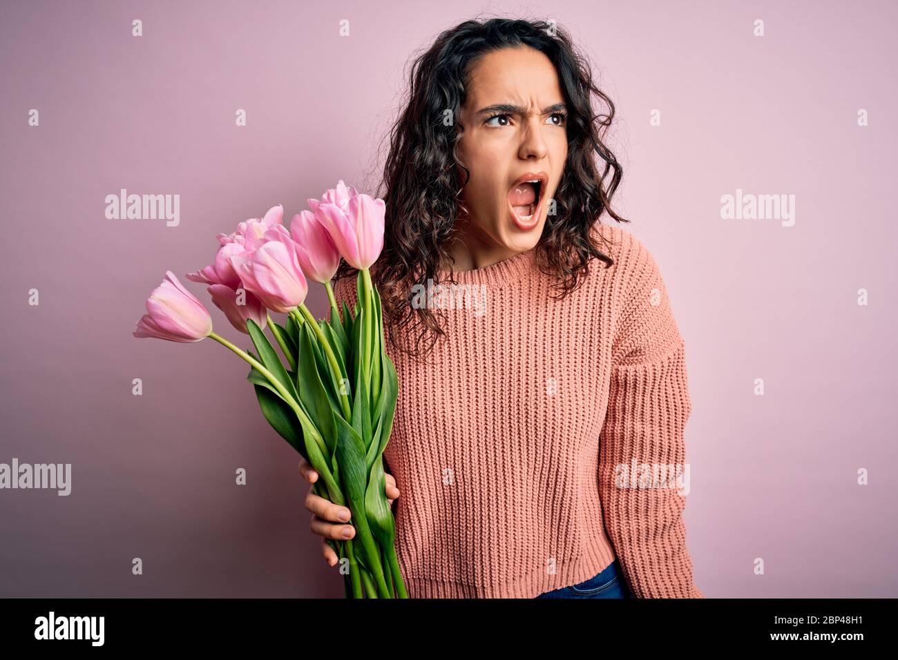 Young beautiful romantic woman with curly hair holding bouquet of pink ...