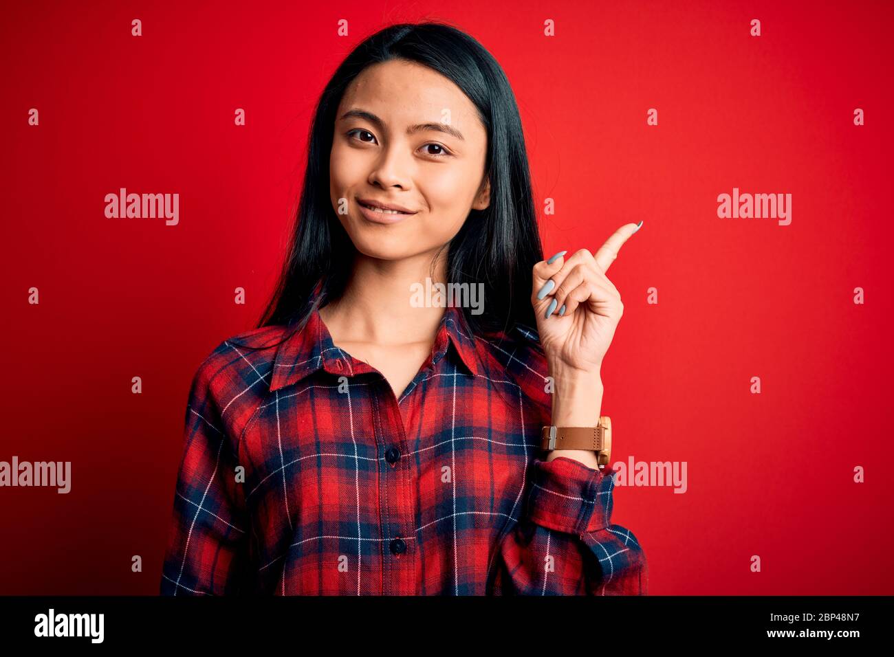 Young beautiful chinese woman wearing casual shirt over isolated red ...