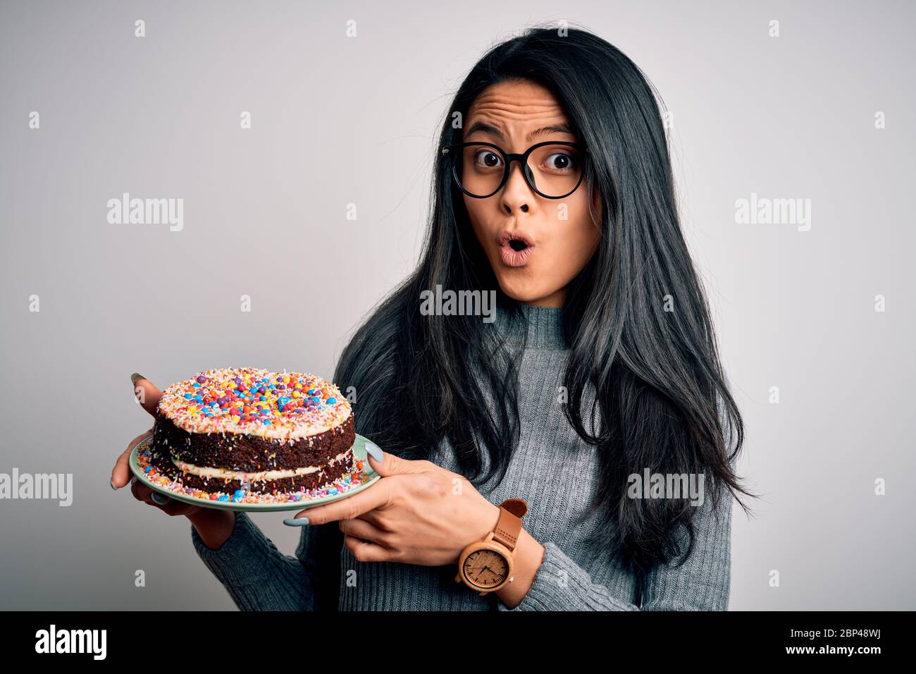 Young beautiful chinese woman holding birthday cake standing over ...