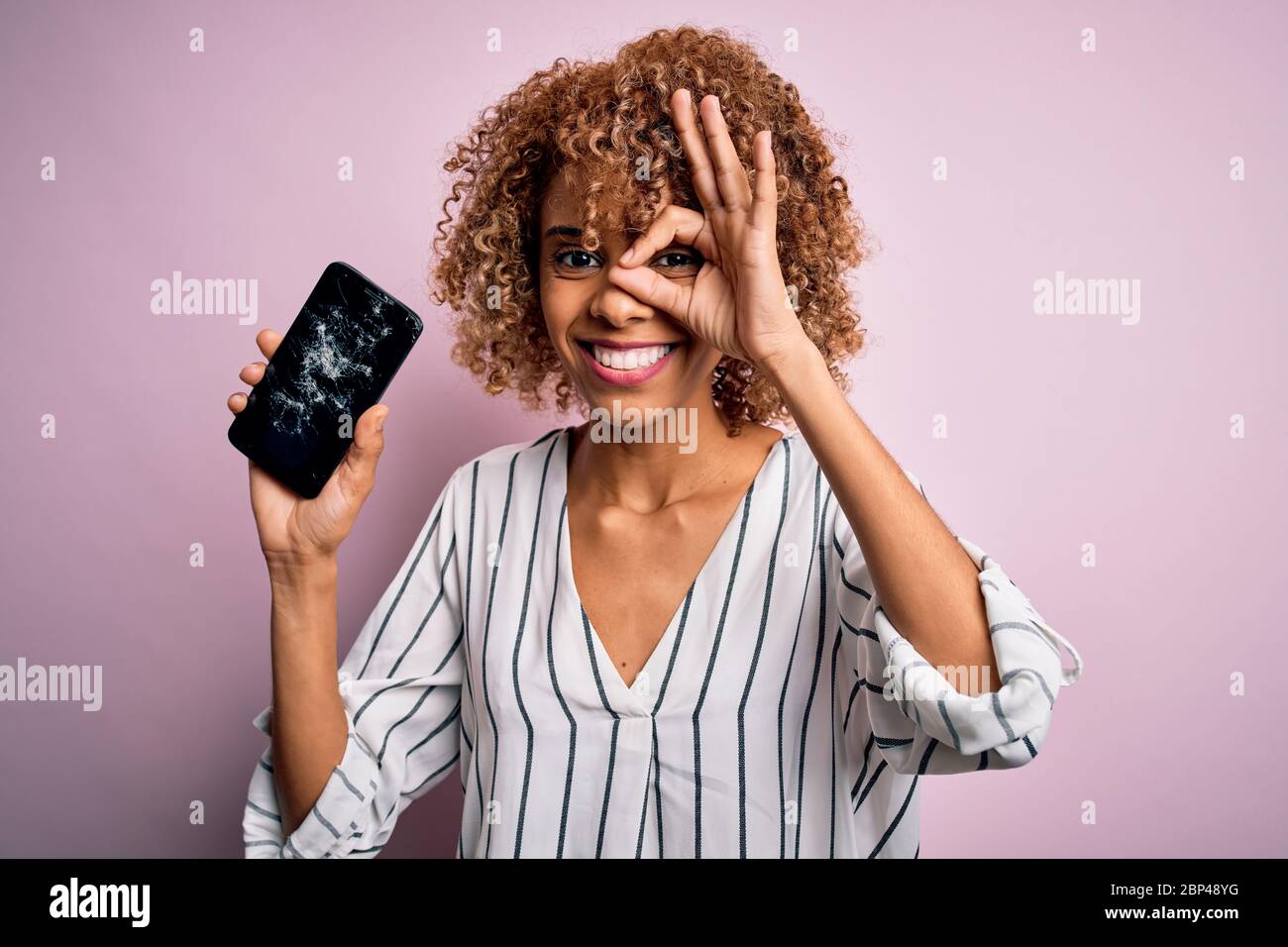 Young african american curly woman holding broken smartphone showing ...