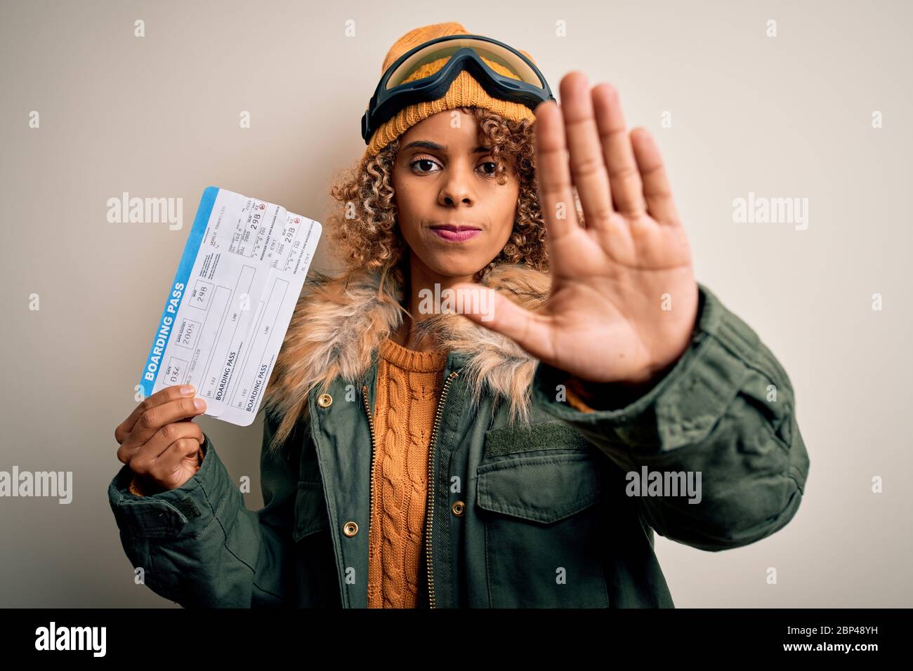 Young african american tourist woman wearing ski goggles holding plane ...