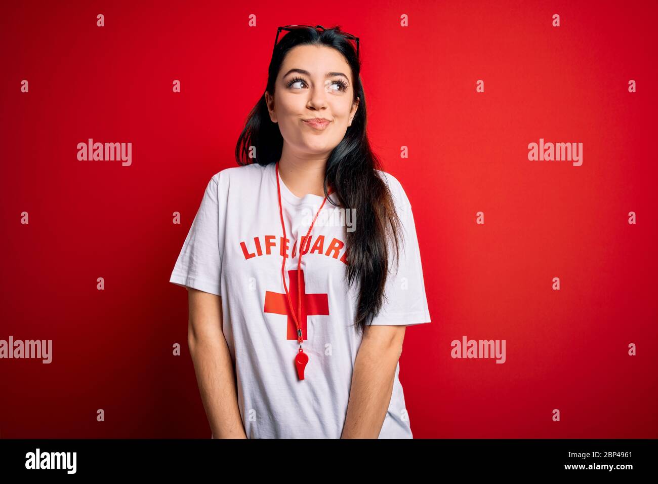 Young lifeguard woman wearing secury guard equipent over red background ...