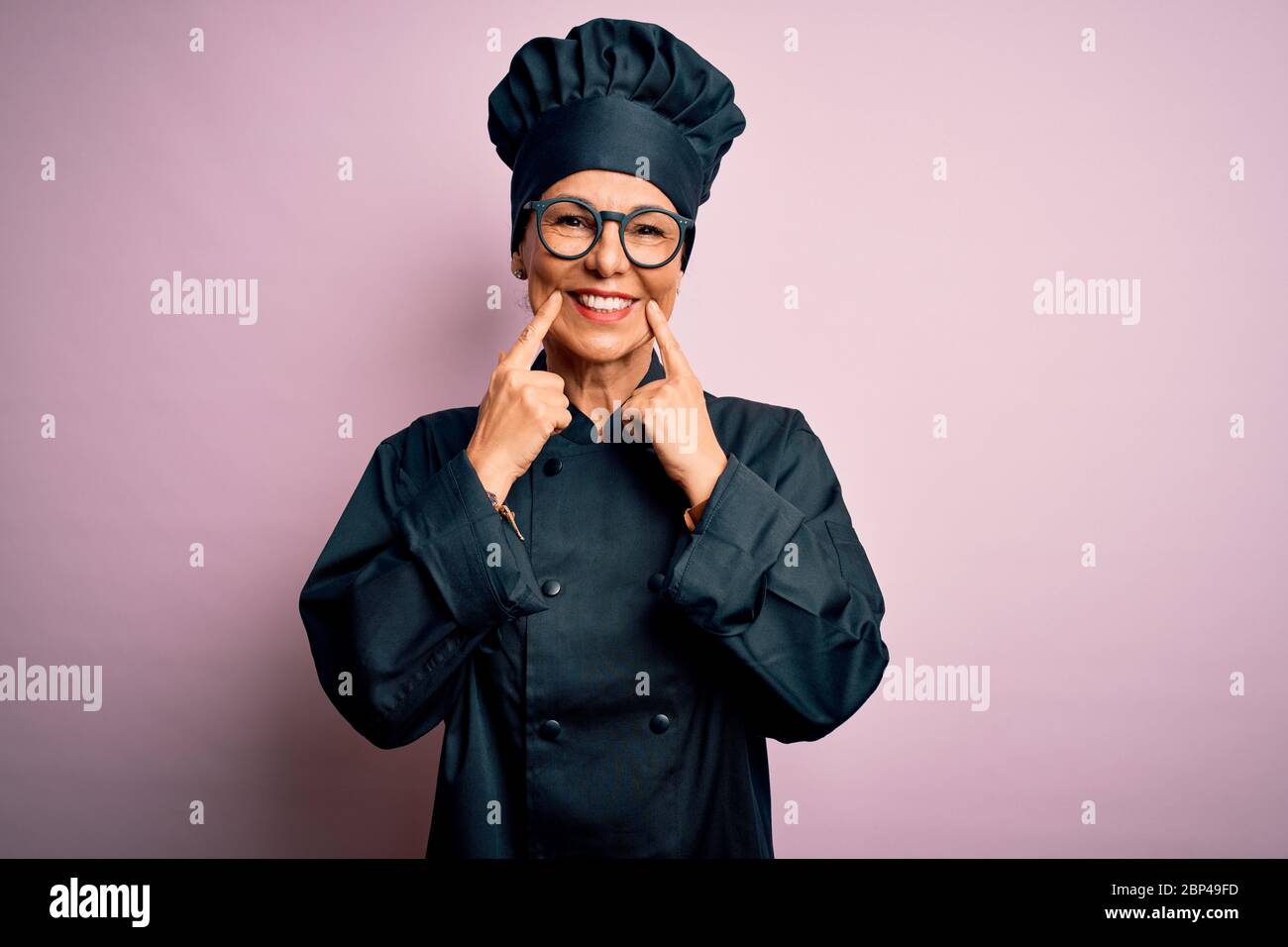 Middle age brunette chef woman wearing cooker uniform and hat over ...