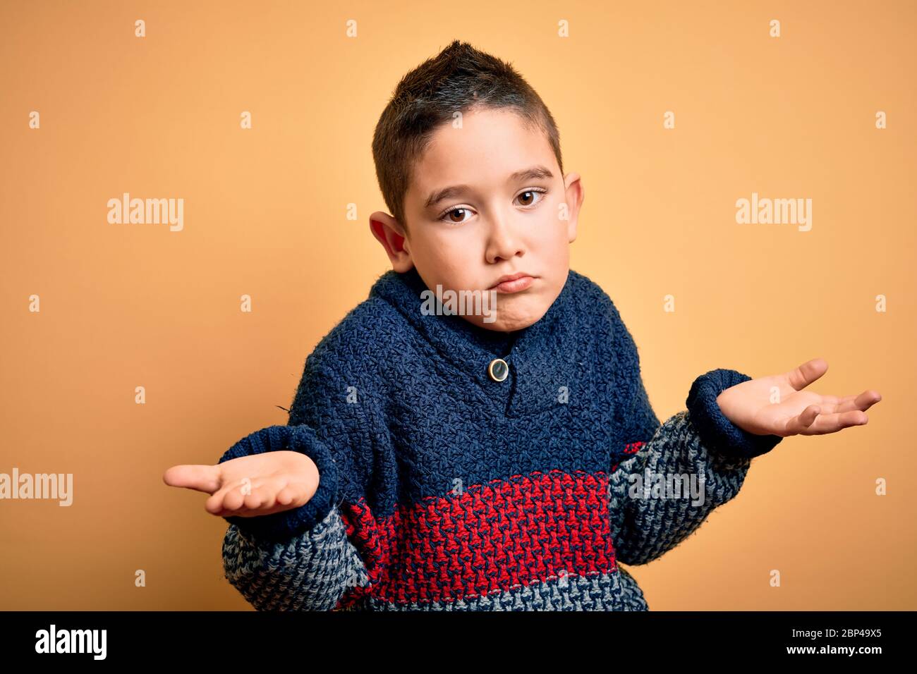 Young little boy kid wearing winter sweater over yellow isolated ...
