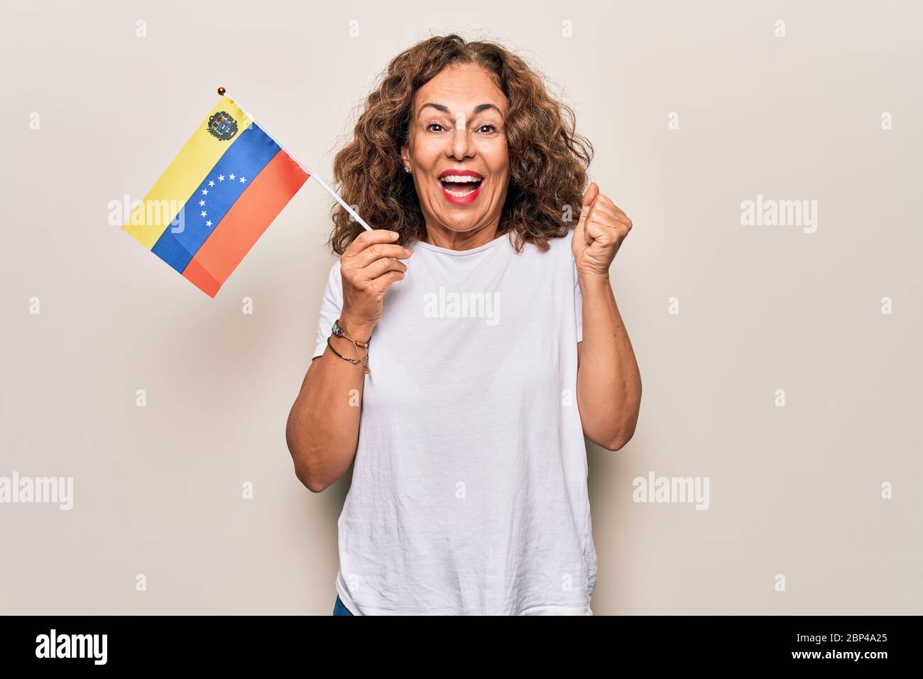 Middle age beautiful tourist woman holding venezuelan flag over ...