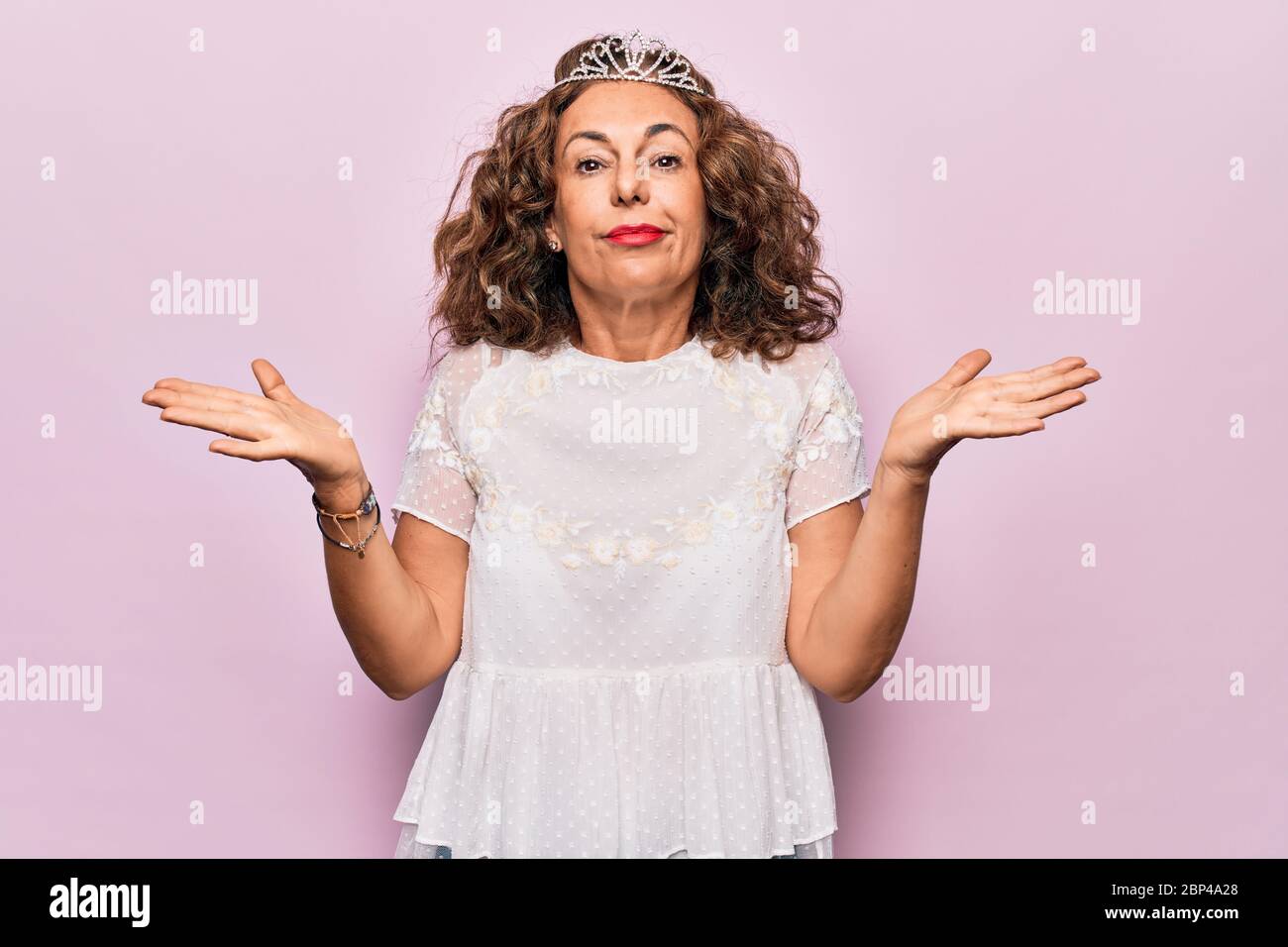 Middle age brunette woman wearing cute princess crown tiara over pink ...