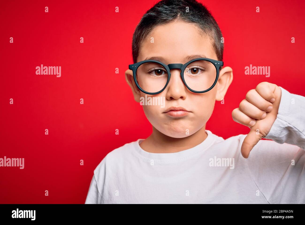 Young little smart boy kid wearing nerd glasses over red isolated ...