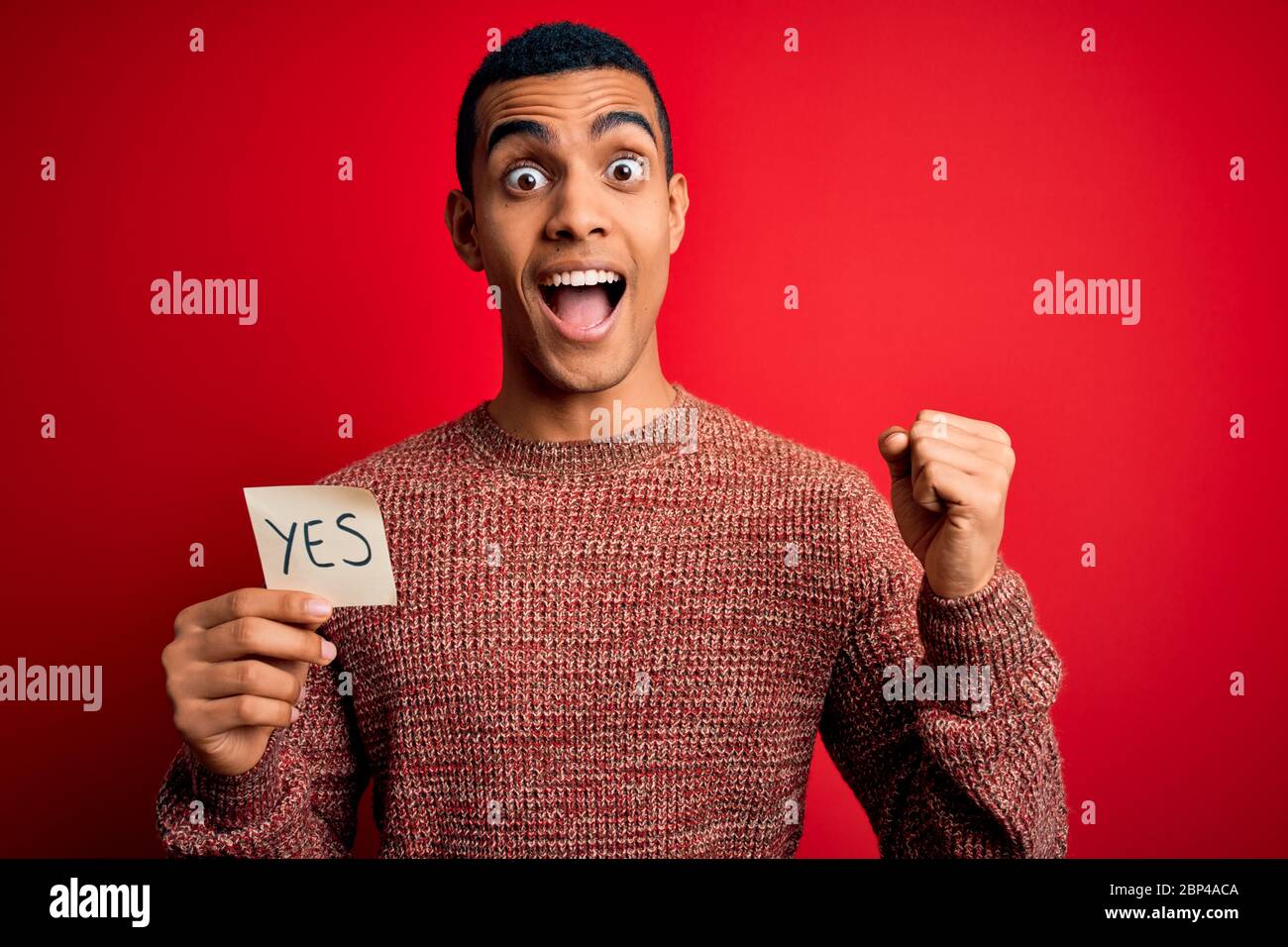 Young handsome african american man holding reminder paper with yes ...