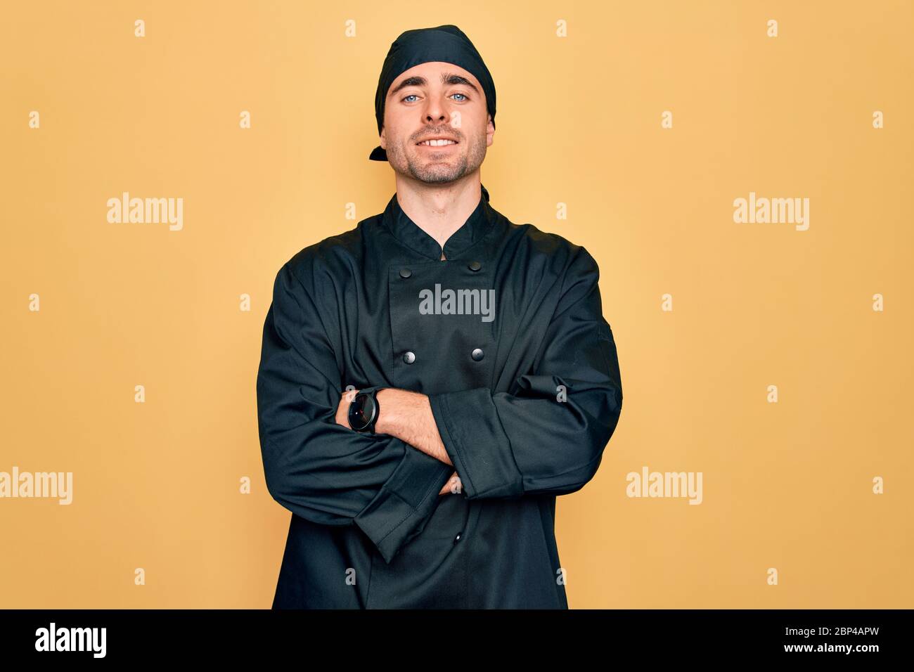 Young handsome cooker man with blue eyes wearing uniform and hat over ...