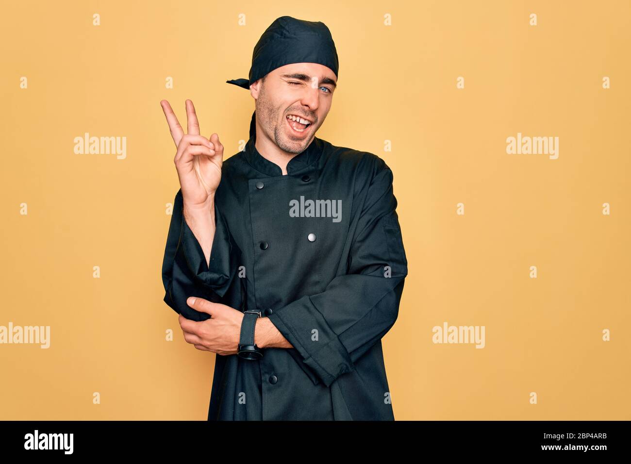 Young handsome cooker man with blue eyes wearing uniform and hat over ...