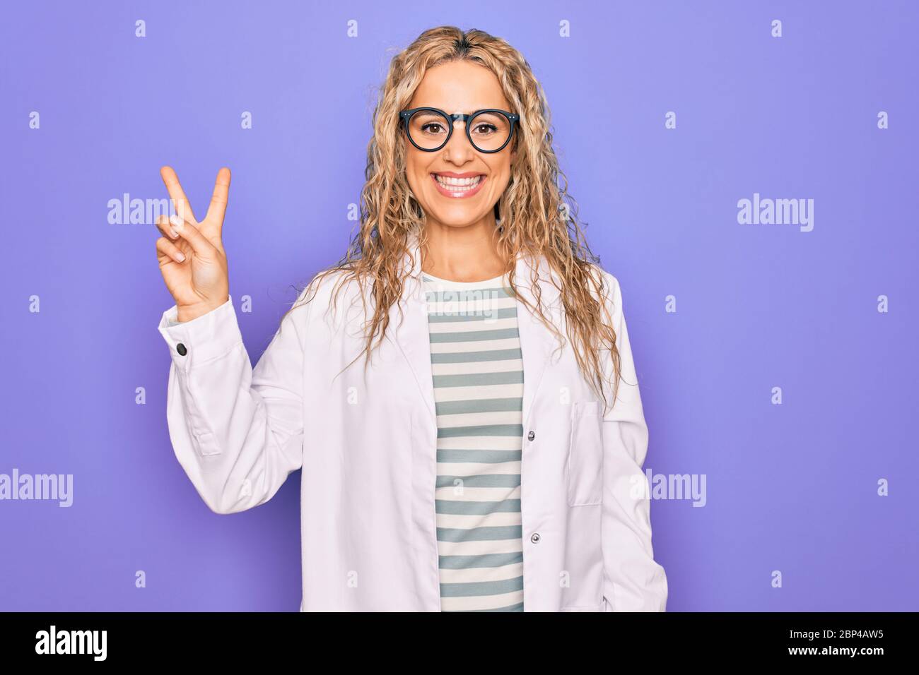 Young beautiful blonde scientist woman wearing coat and glasses over ...