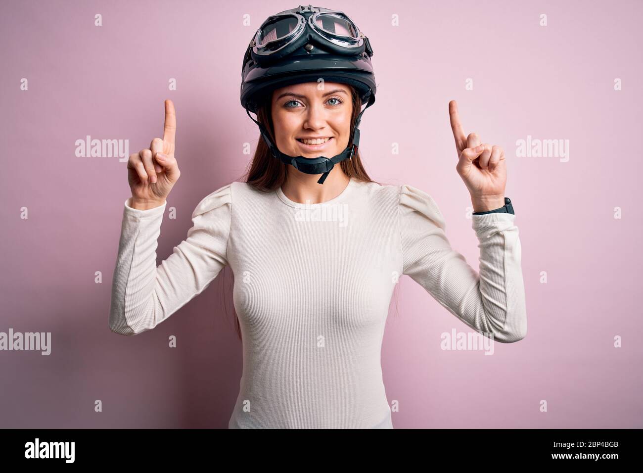 Young beautiful motorcyclist woman with blue eyes wearing moto helmet ...
