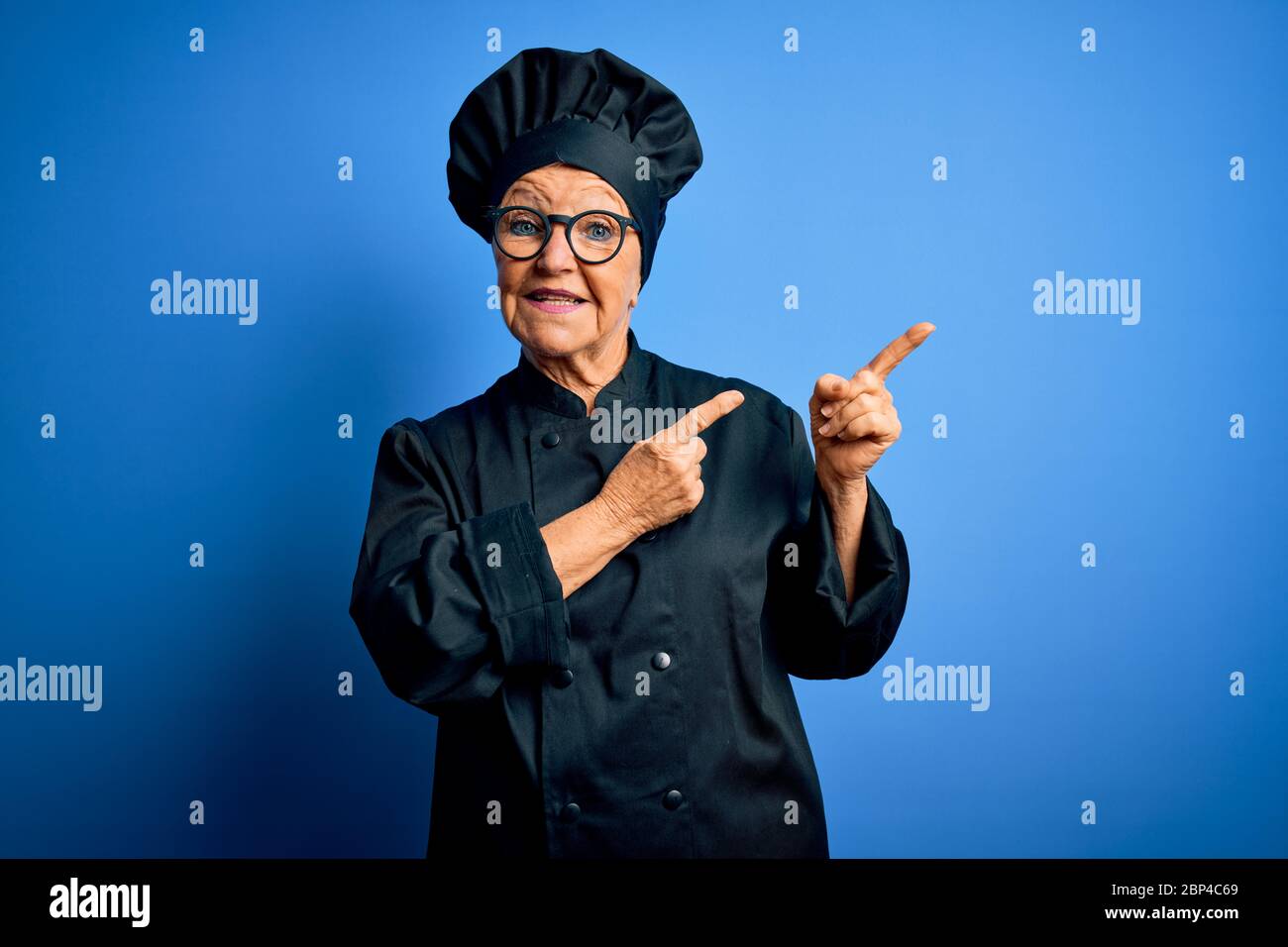 Senior beautiful grey-haired chef woman wearing cooker uniform and hat ...