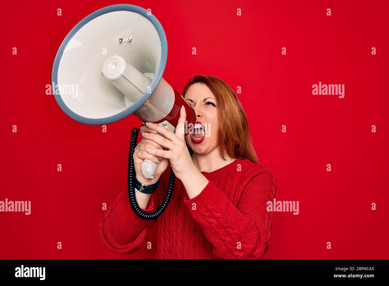 Young beautiful redhead speaker woman screaming communicate using ...