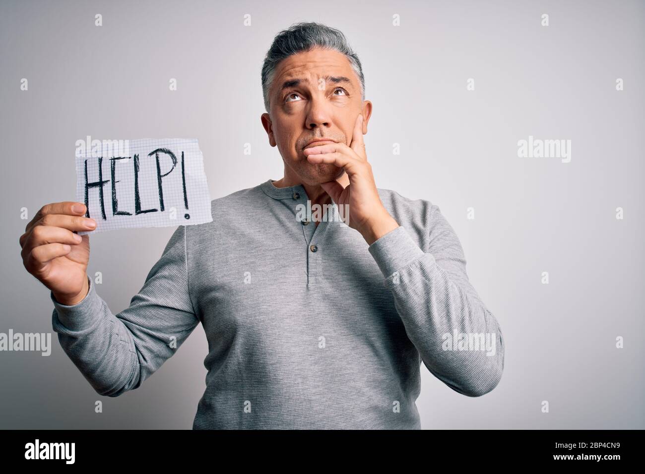 Middle age handsome grey-haired man holding paper with help message ...