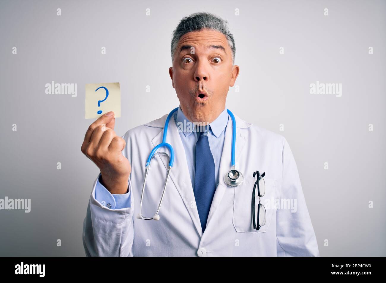 Middle age handsome grey-haired doctor man holding paper with question ...
